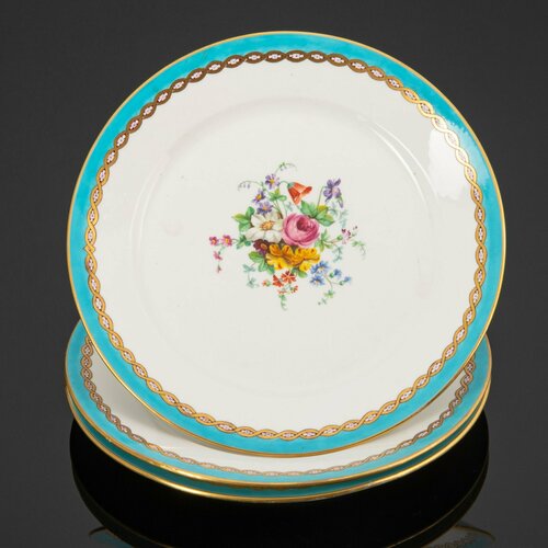 Набор тарелок, украшенных вьющимся орнаментом и букетом цветов по центру
